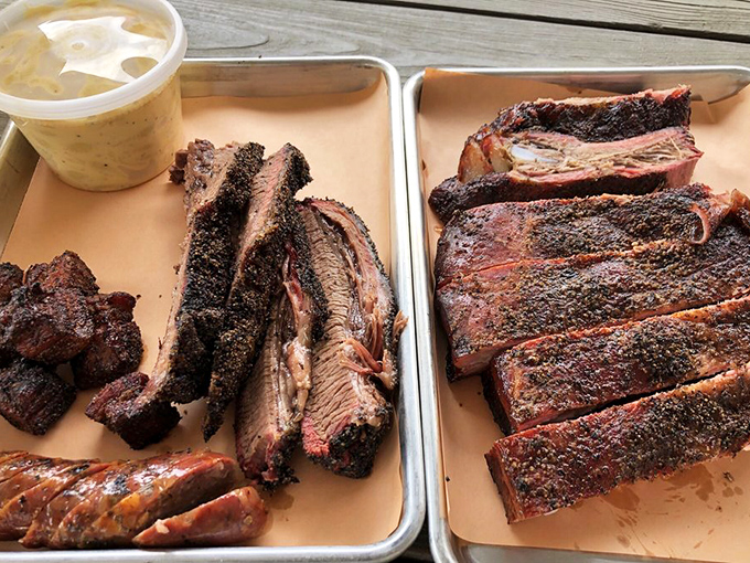 When someone asks what happiness looks like, just show them this image of perfectly smoked meats alongside classic Southern sides.
