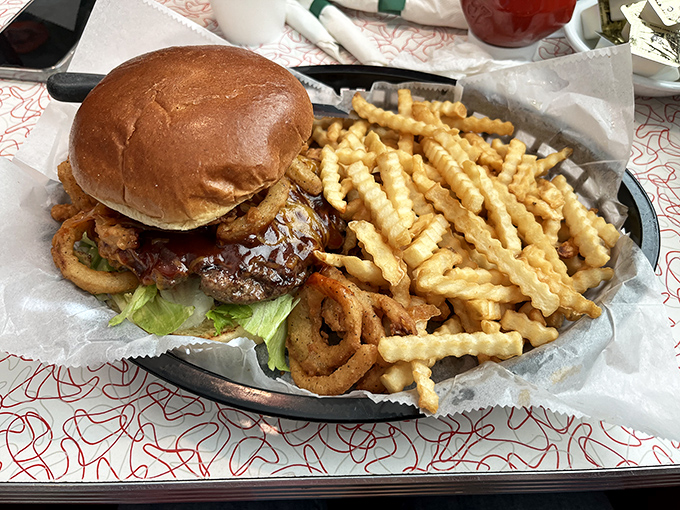 A burger that requires both hands and a strategy, accompanied by crinkle-cut fries that achieve the perfect balance between crisp exterior and fluffy interior.