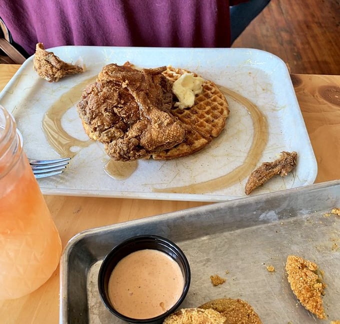 The waffle serves as both plate and companion to perfectly fried chicken, with crinkle-cut fries playing the role of delicious supporting actor.