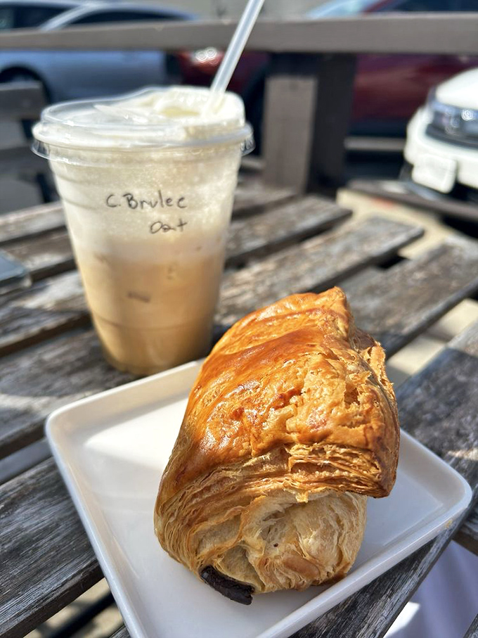 Coffee's perfect dance partner: a cr&egrave;me br&ucirc;l&eacute;e oat latte alongside a croissant with layers so delicate they practically whisper French poetry.