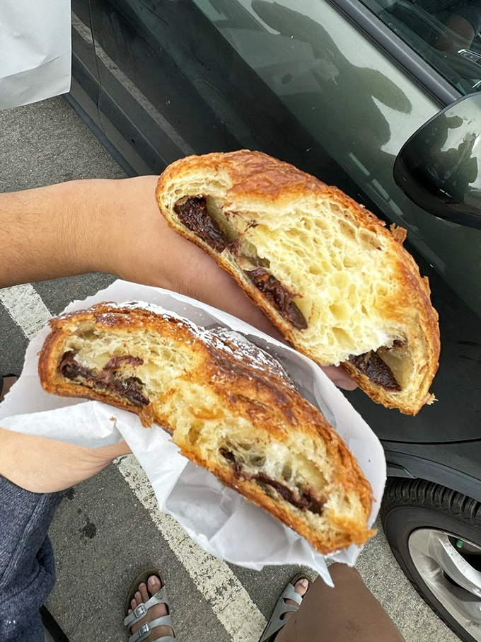 The chocolate croissant, split open to reveal its treasure, like a delicious X-ray of what joy actually looks like inside.