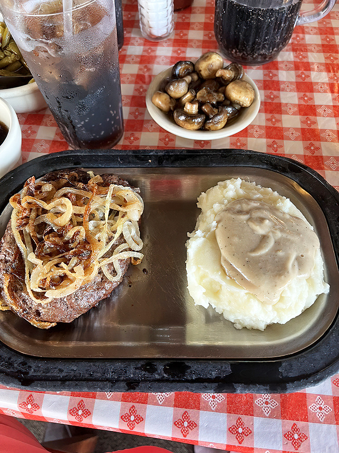A hamburger steak lounging on its metal throne, accompanied by a cup of au jus that's practically begging you to dunk each savory bite.