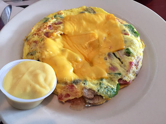This omelet doesn't just contain ingredients; it embraces them. A fluffy yellow blanket tucking in vegetables and cheese with loving care.