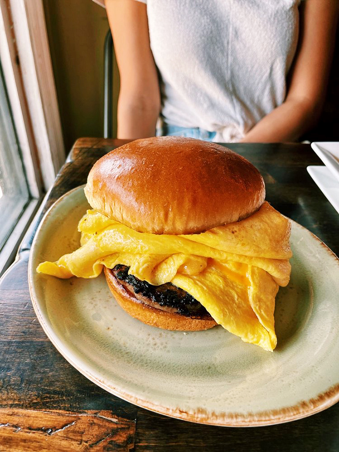 This isn't just a breakfast sandwich&mdash;it's morning architecture with pillowy brioche, folded eggs, and what looks like savory sausage.