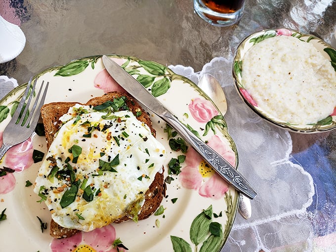 Sunny-side up perfection atop avocado toast, sprinkled with herbs and spices. Grits on the side because, well, this is Alabama after all.