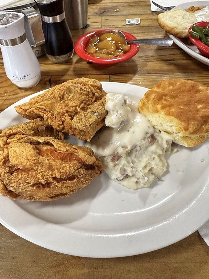 If Norman Rockwell painted the ideal plate of fried chicken, it would look exactly like this – golden, glistening, and nestled next to mashed potatoes and greens.
