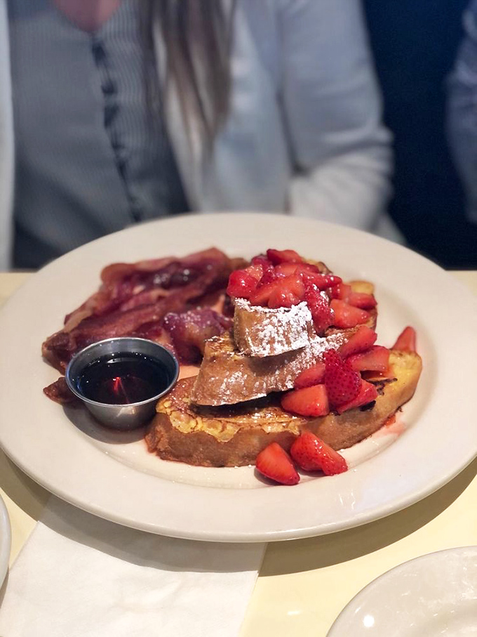 French toast that makes breakfast feel like dessert, with fresh strawberries and powdered sugar playing supporting roles to the main attraction.
