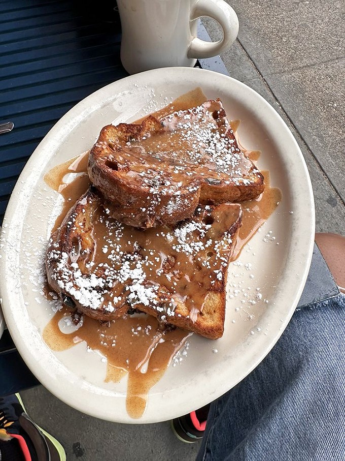 French toast that's achieved breakfast nirvana &ndash; thick-cut, perfectly caramelized, and dripping with maple syrup and powdered sugar confetti.