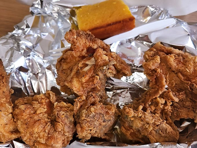 Golden-brown fried chicken and cornbread served on humble foil—proof that the most memorable food experiences often come without fancy presentation.