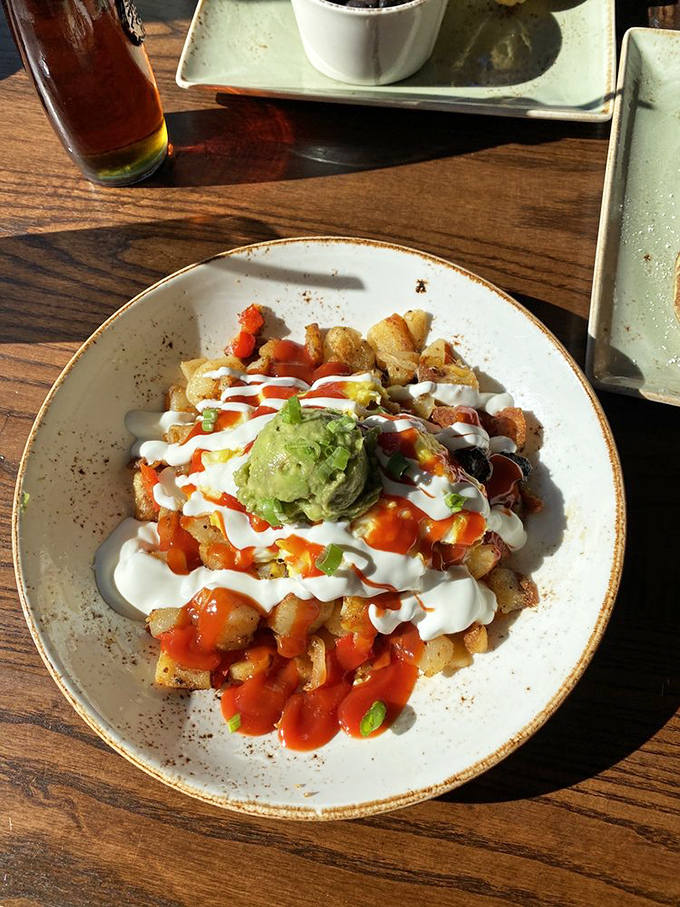 Breakfast potatoes living their best life, dressed in creamy sauce, hot sauce, and a crown of avocado&mdash;potato royalty on a plate.