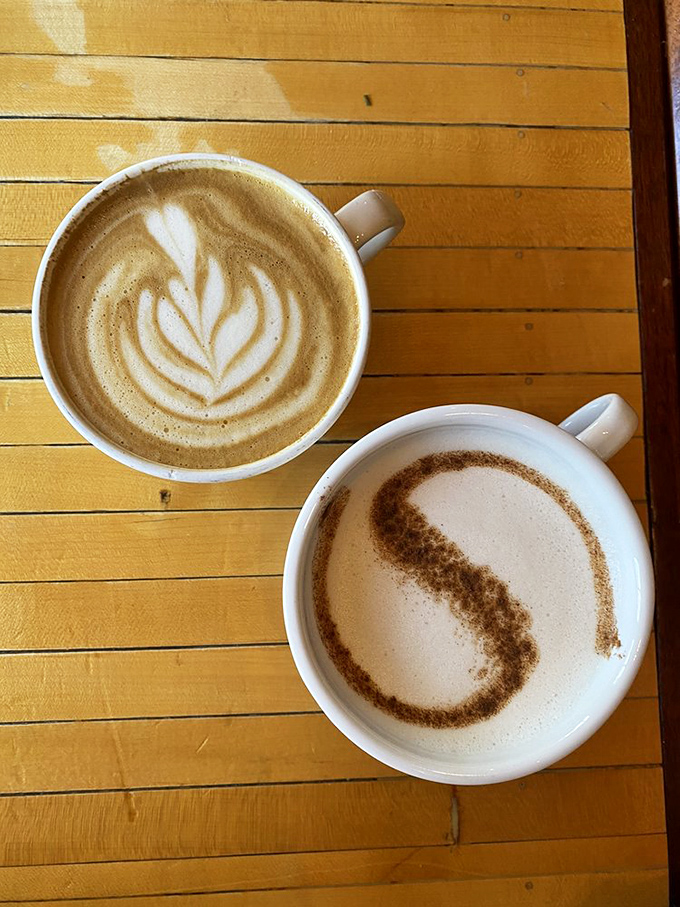 Two cups of morning magic – one sporting a delicate leaf, the other with what appears to be the world's most caffeinated yin-yang symbol.