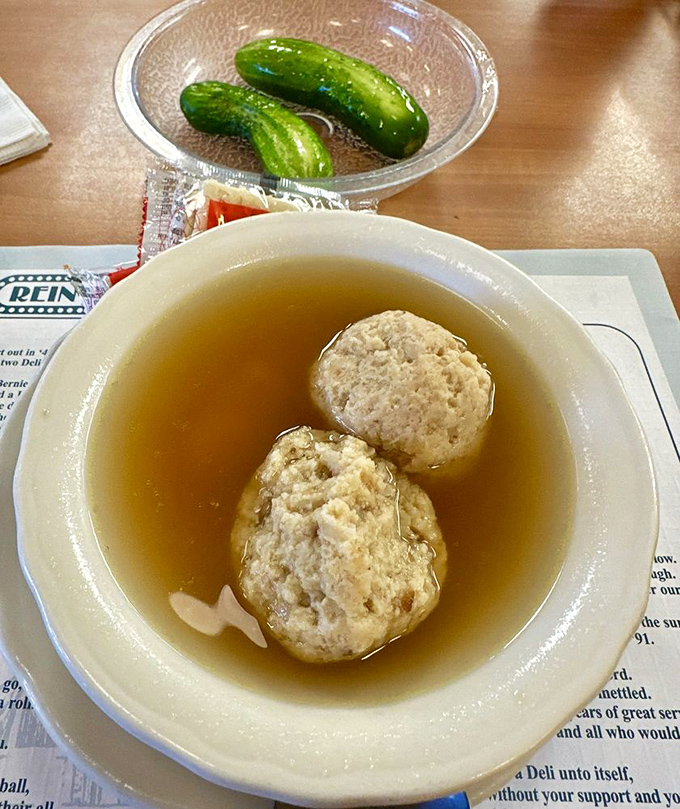 The holy trinity of deli dining: matzo ball soup, half-sour pickles, and the anticipation of the sandwich that's about to change your day.