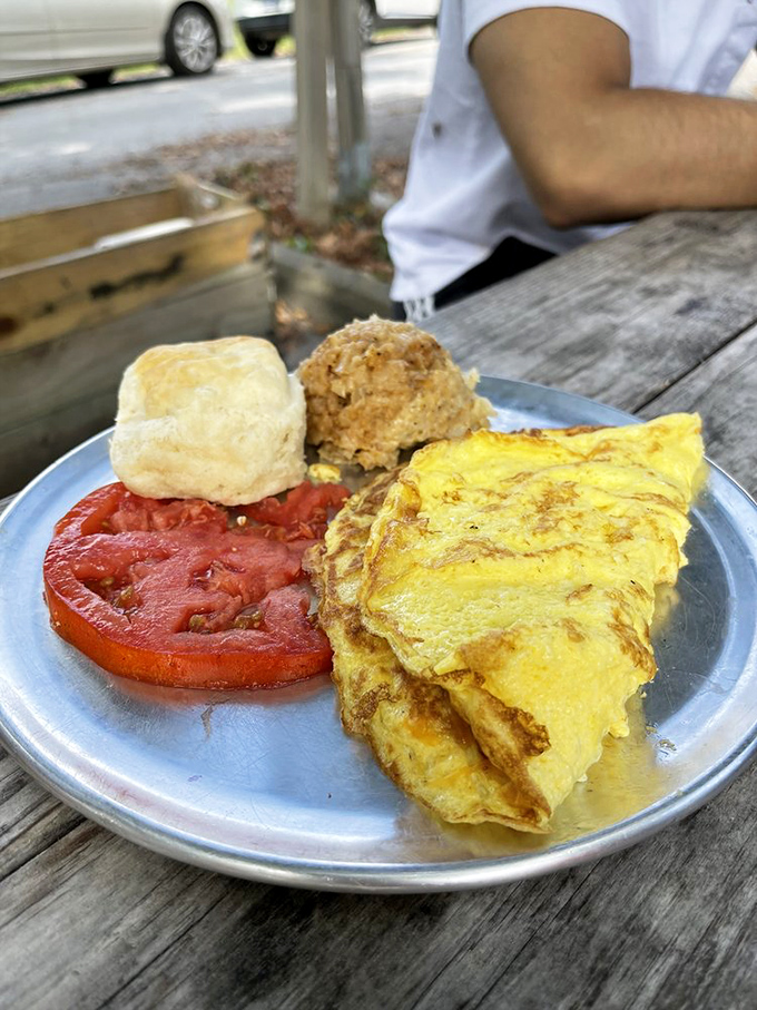 This isn't just an omelet; it's a perfectly executed breakfast sonnet with a side of biscuit and sliced tomato for good measure.