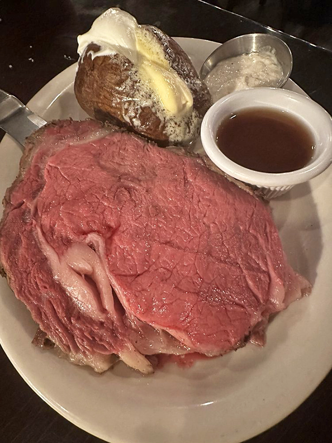 Rare prime rib that's practically blushing from all the attention, with a loaded baked potato that's dressed for the occasion.