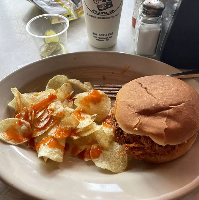 The pulled pork sandwich doesn't need fancy dress-up. Just meat, bread, and chips with sauce drizzled like abstract art for your taste buds.
