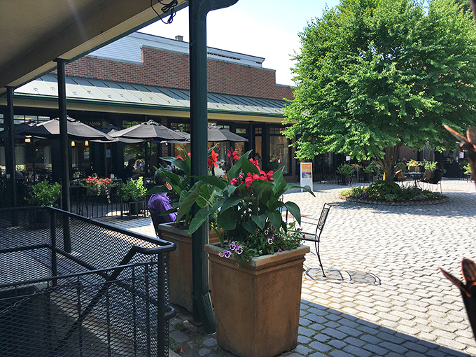 This inviting courtyard offers a peaceful respite from shopping, where cobblestones and flowering plants create the perfect spot for people-watching.