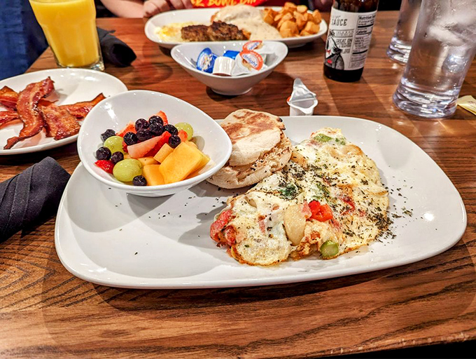 A table spread worthy of a weekend celebration: fresh fruit, crispy bacon, and an omelet that puts your standard breakfast to absolute shame.
