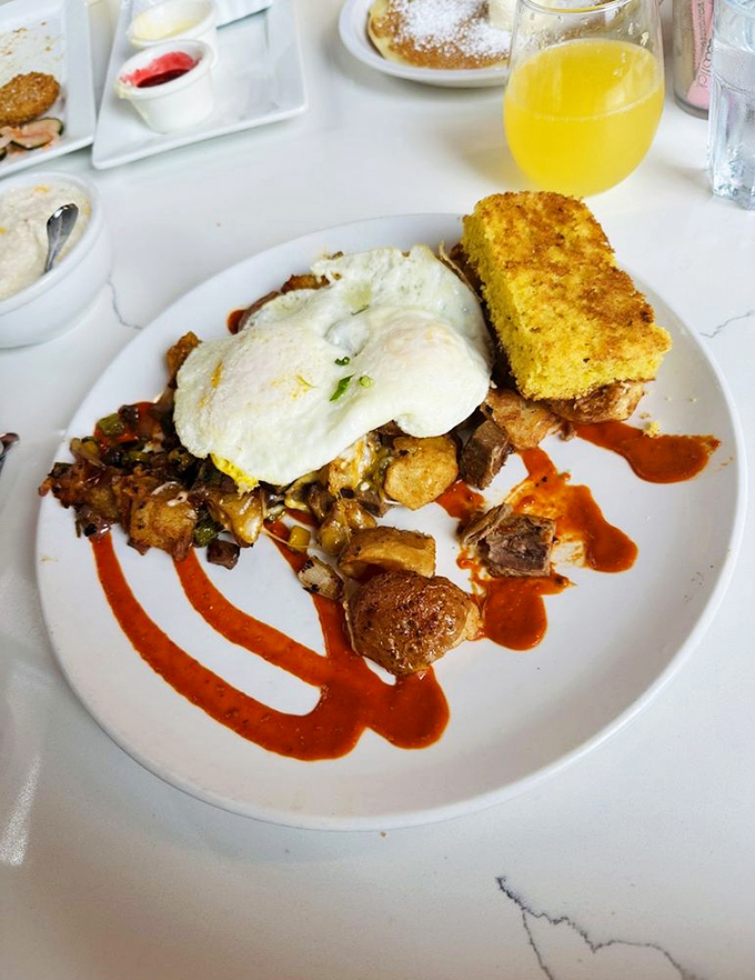 Breakfast architecture at its finest &ndash; layers of flavor built on a foundation of potatoes, crowned with eggs and artistic sauce flourishes.