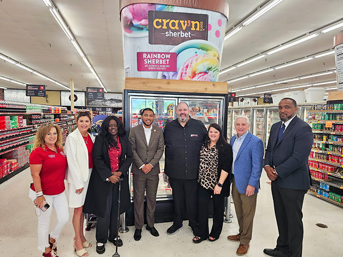 A gathering of what appears to be community members or visitors near the frozen section&mdash;grocery shopping as a social experience.