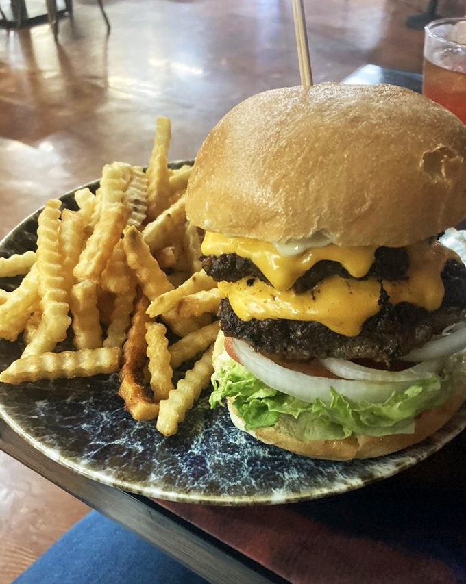 The DinoLand Burger stands tall like a geological formation of beef and cheese. Those crinkle-cut fries are the perfect sidekick to this meaty monument.