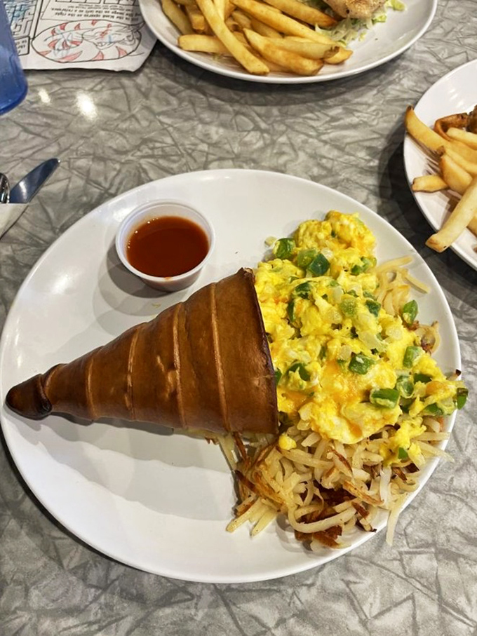 Breakfast reimagined! Fluffy scrambled eggs with green peppers nestled beside crispy hash browns and a perfectly golden croissant.