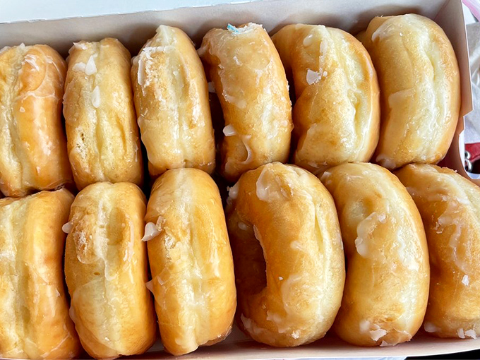 Perfectly aligned glazed donuts await their destiny. Like soldiers of sweetness, they stand ready to brighten someone's morning. 