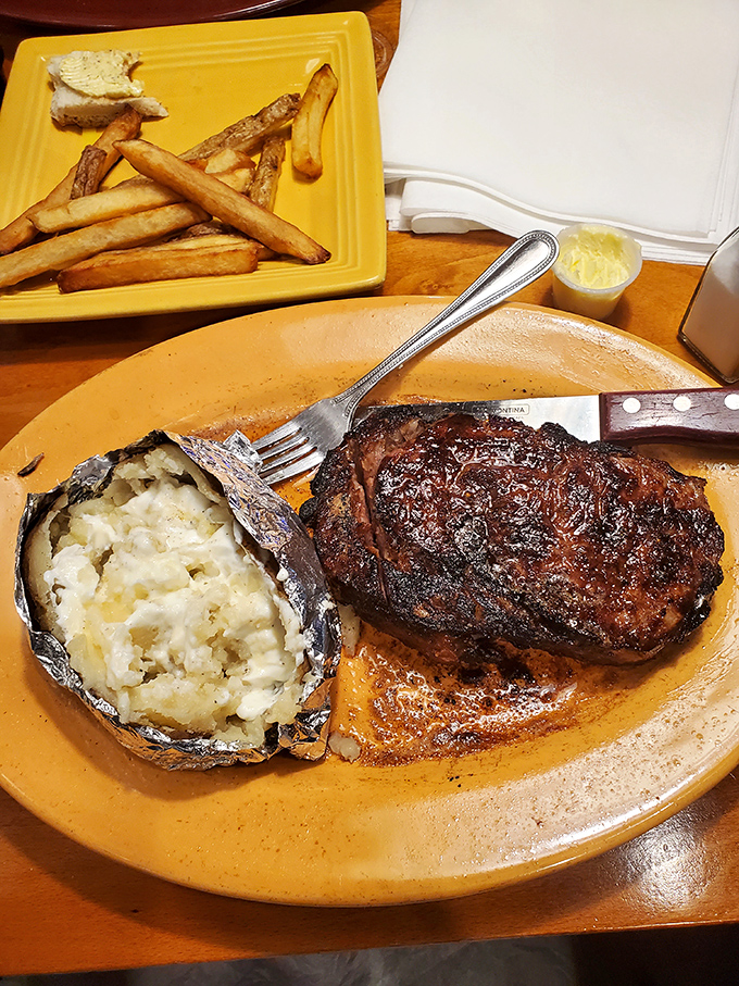 The classic steakhouse pairing: a glorious cut of beef alongside a foil-wrapped potato bursting with fluffy, buttery goodness.