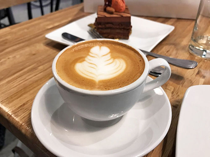 Latte art so beautiful you almost feel guilty disturbing it &ndash; almost. That chocolate cake in the background isn't helping with self-control.