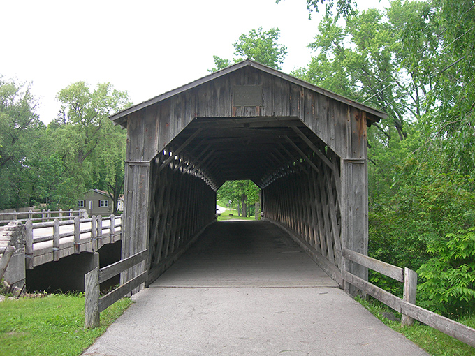 The Covered Bridge whispers stories of horse-drawn carriages and Sunday drives, its weathered timbers sheltering travelers just as they did in 1876.