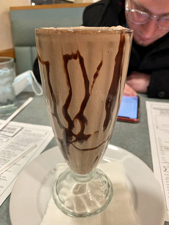 Chocolate milkshake art with syrup drizzles that would make Jackson Pollock proud – dessert and entertainment in one frosty glass.