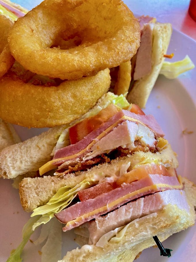 The club sandwich&mdash;architecture you can eat, layered with precision and served with onion rings that crunch loud enough to turn heads.