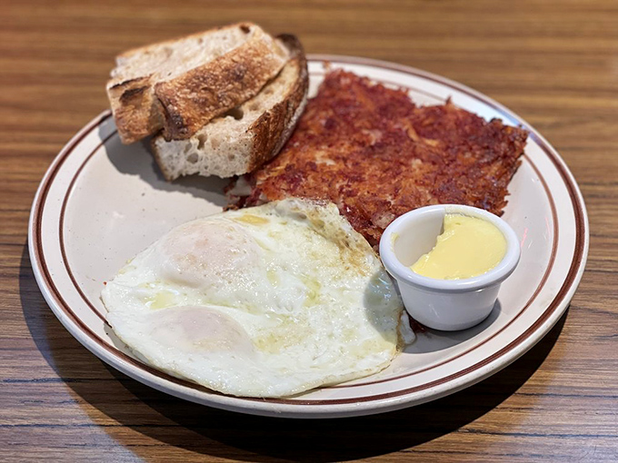 The holy trinity of breakfast: perfectly fried egg, crispy corned beef hash, and toast waiting patiently to soak up every last bit.