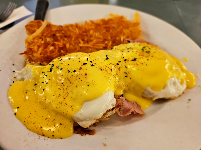 Hollandaise sauce cascading over eggs Benedict like a yellow waterfall of happiness. Those hash browns deserve their own fan club.