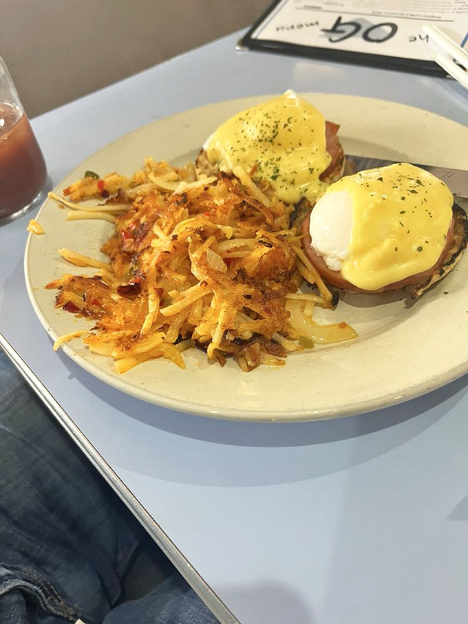 Eggs Benedict done right—hollandaise cascading over English muffins like a sunrise, with hash browns crisped to golden perfection.