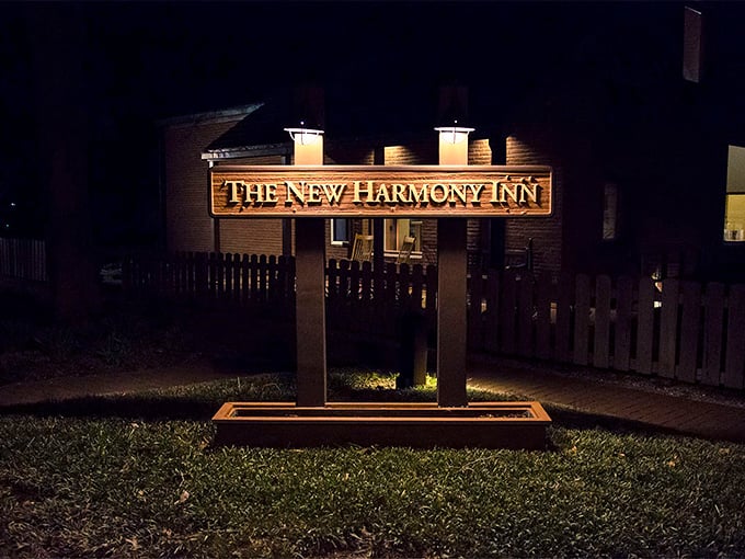 The New Harmony Inn sign glows like a beacon for weary travelers, promising a night's rest steeped in history and Hoosier hospitality.