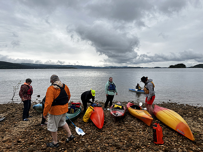 Kayak enthusiasts preparing for aquatic exploration. Even under moody skies, these colorful vessels promise adventures that no Netflix series could ever match.