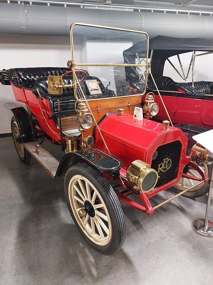 This magnificent red touring car, with its gleaming brass fittings and wooden wheels, represents the dawn of America's love affair with automobiles.
