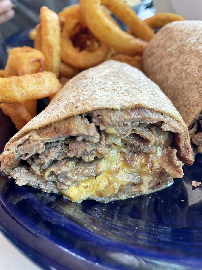 When cheese, steak, and bread achieve perfect harmony in a wrap that's portable yet profound. The onion rings are just showing off at this point.