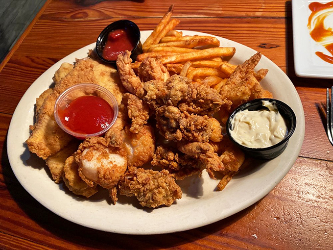 The fried seafood platter arrives like treasure from Davy Jones' locker, golden-brown treasures from the deep accompanied by crispy fries.