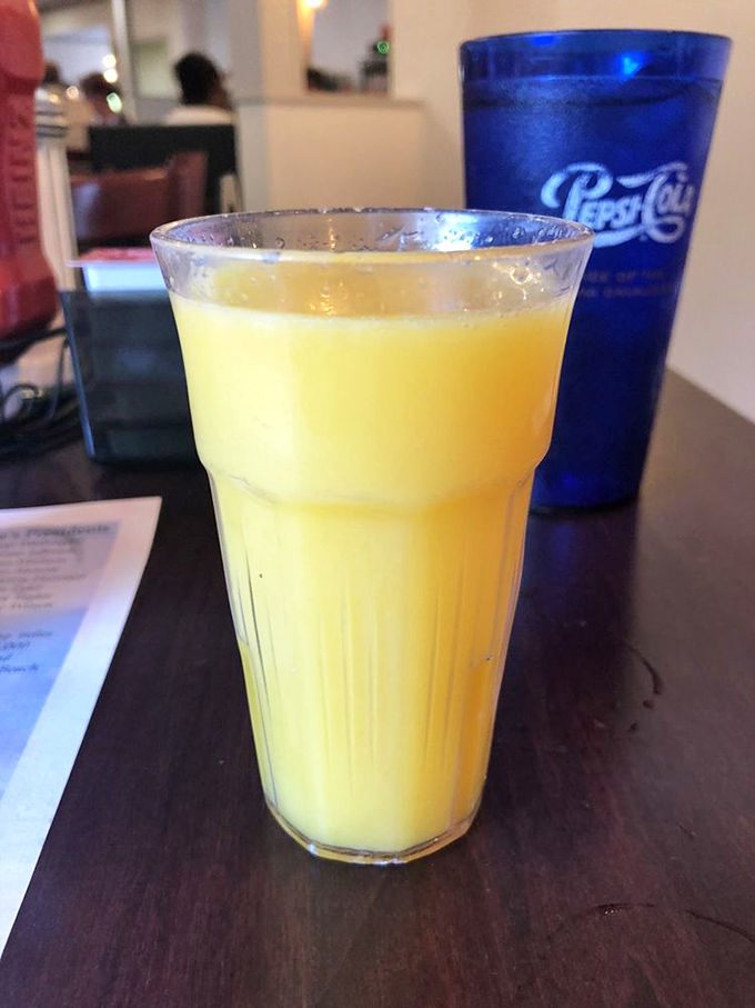 Fresh orange juice glowing like liquid sunshine in a sturdy glass. The perfect companion to cut through all that delicious breakfast richness.
