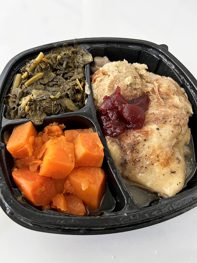 A compartmentalized masterpiece: tender chicken, vibrant collards, and candied yams that taste like someone's grandmother made them with love.