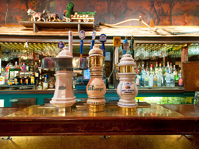 The bar, where German beer steins stand proudly like ceramic sentinels guarding liquid treasures from the Old World.