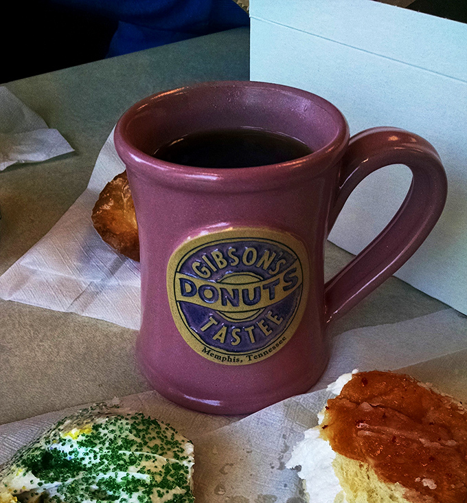 A Gibson's coffee mug stands guard over colorful donut soldiers, ready for the delicious battle between caffeine and sugar to commence.