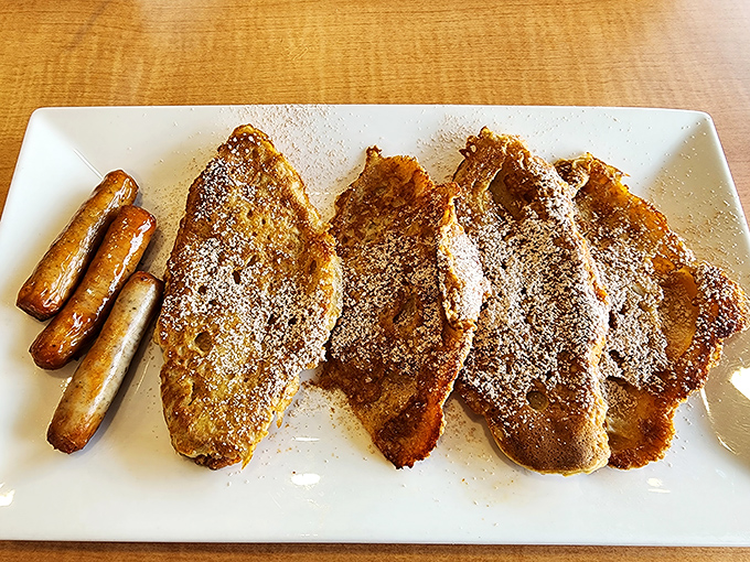 Sausage links stand guard beside French toast soldiers, a breakfast alliance powerful enough to conquer even the most stubborn morning grouch.
