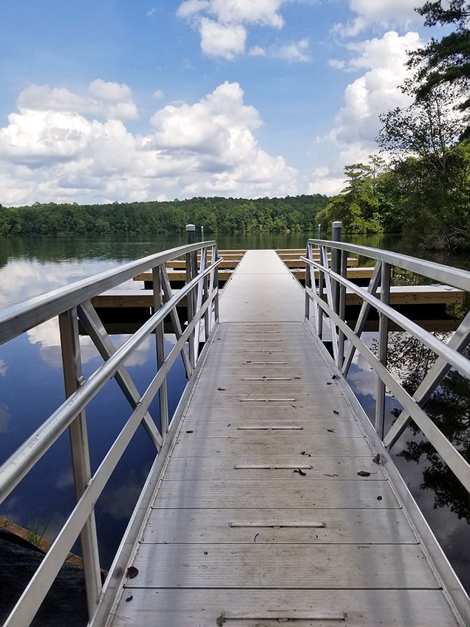 The fishing pier extends like an invitation into the glassy lake. Cloud reflections create nature's perfect mirror&mdash;no Instagram filter required.