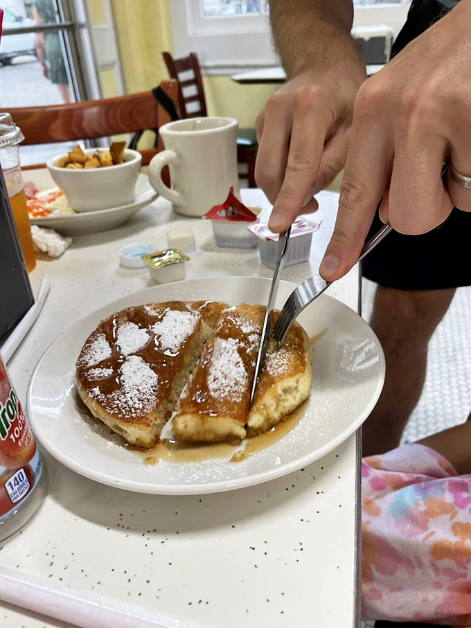 Pancakes drowning happily in syrup, dusted with powdered sugar. The kind of breakfast that makes you want to cancel your plans and order seconds.