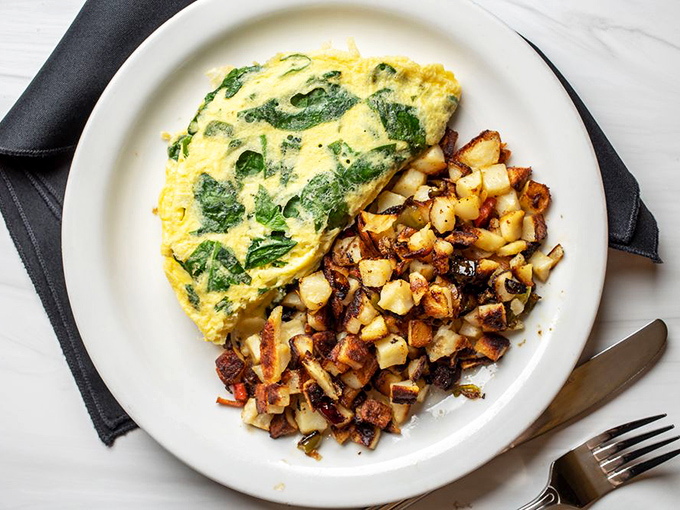 This isn't just any omelet&mdash;it's a fluffy yellow pillow stuffed with vibrant spinach, paired with potatoes crisped to golden perfection.