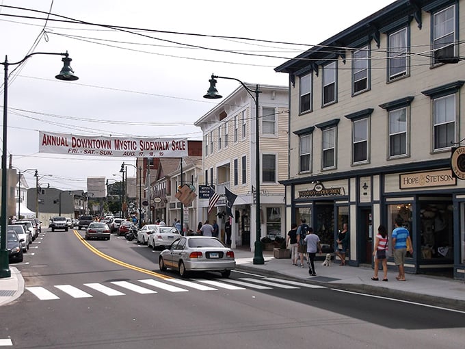 Mystic's charming downtown welcomes visitors with its annual sidewalk sale banner, promising small-town shopping adventures.