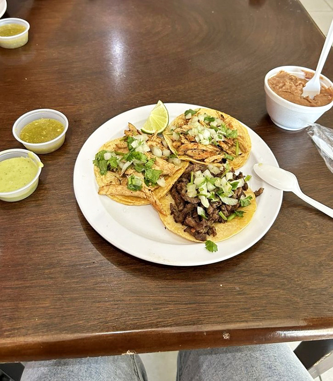 A trio of tacos demonstrating why sometimes the simplest presentations – meat, cilantro, onion, lime – create the most profound flavor experiences.
