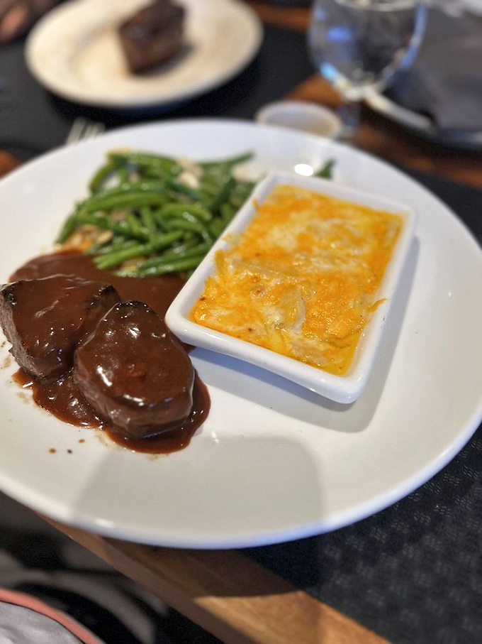 Beef medallions bathed in rich sauce, flanked by green beans and cheesy potatoes&mdash;the holy trinity of steakhouse perfection.